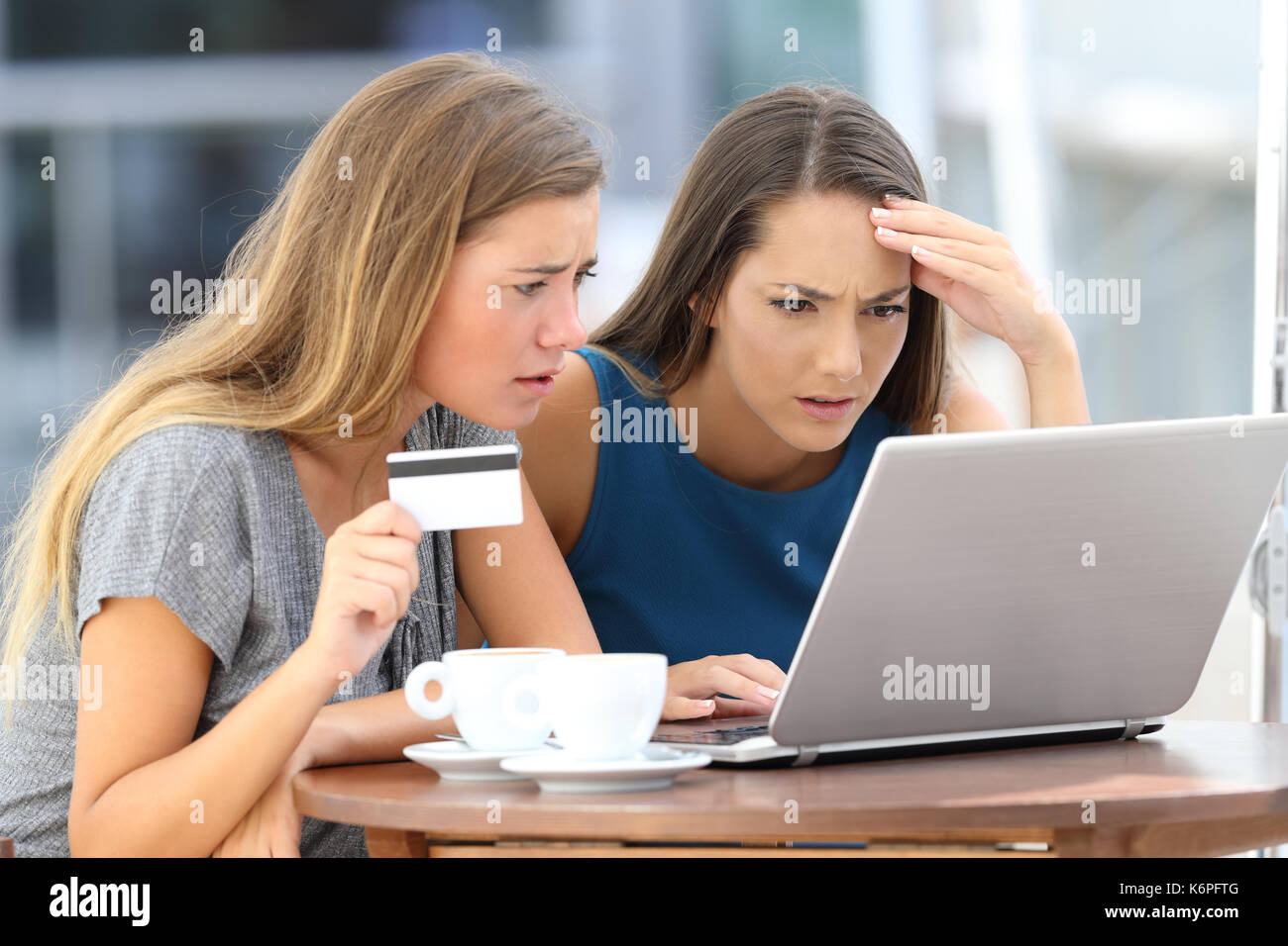 Two worried women having problems buying on line with a laptop and ...