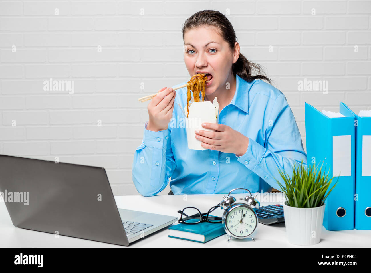 Very hungry girl with noodles in the office Stock Photo - Alamy