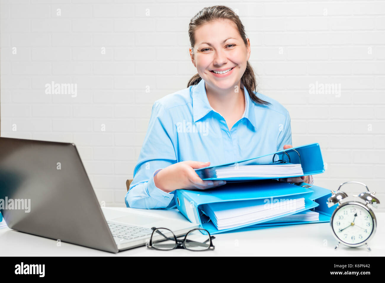 Happy accountant with folders at the table on a bricky white wall ...