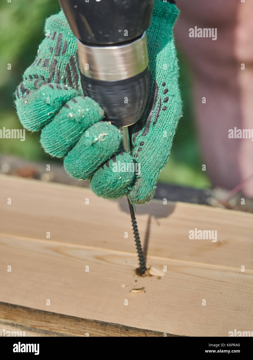 The builder screws the screw into the board Stock Photo - Alamy