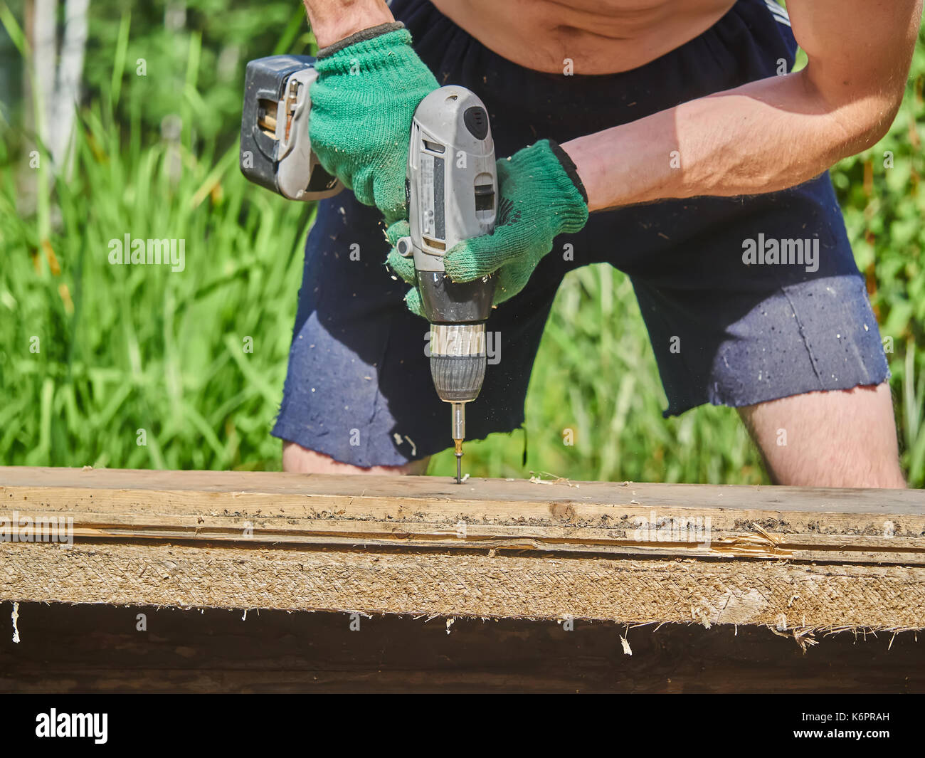 The builder screws the screw into the board Stock Photo - Alamy