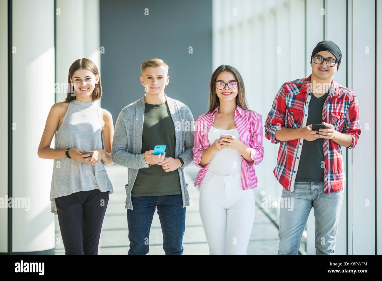 Group of young friends looking at their smart phones without ...