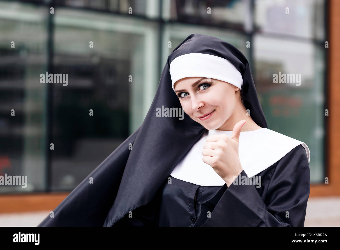 Young happy nun giving thumbs up outdoors Stock Photo - Alamy