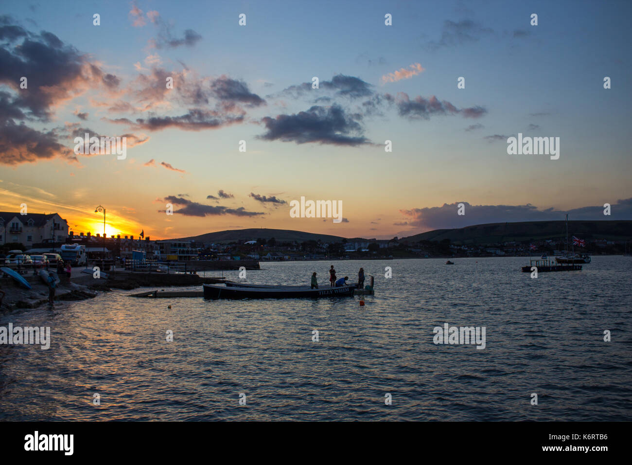 Docking boat with people silhouettes at sunset, seafront of Swanage ...