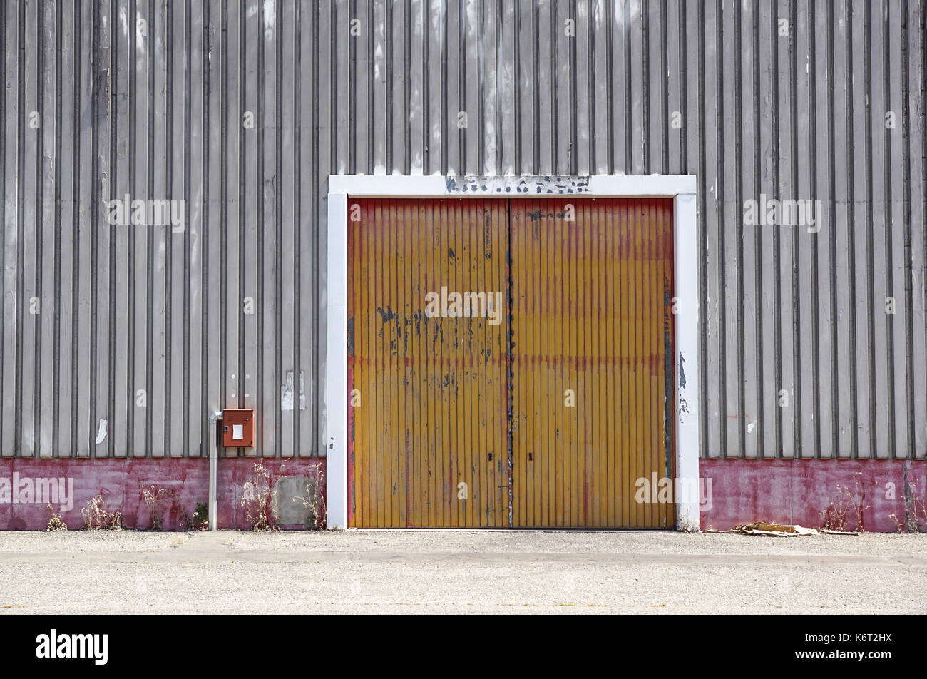 The sheet metal factory wall with the red entrance door in the ...