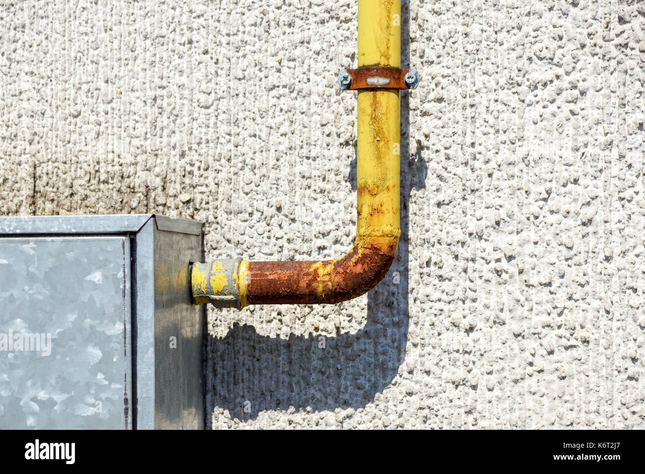 Old water metal pipes fixed with brackets in front of a plaster wall ...