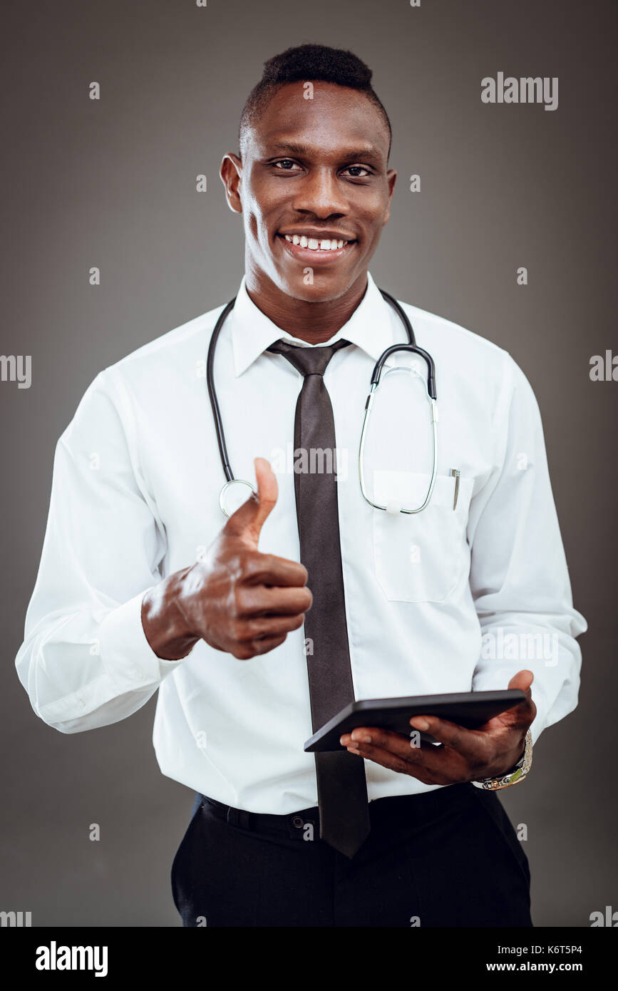 African smiling doctor with stethoscope standing and using digital ...