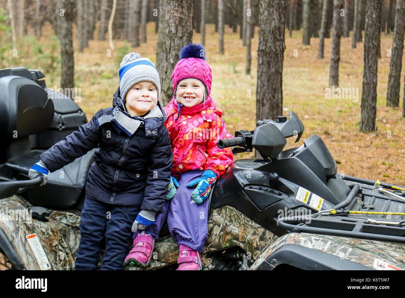 Two little caucasian kids sitting on an ATV and having fun together in ...