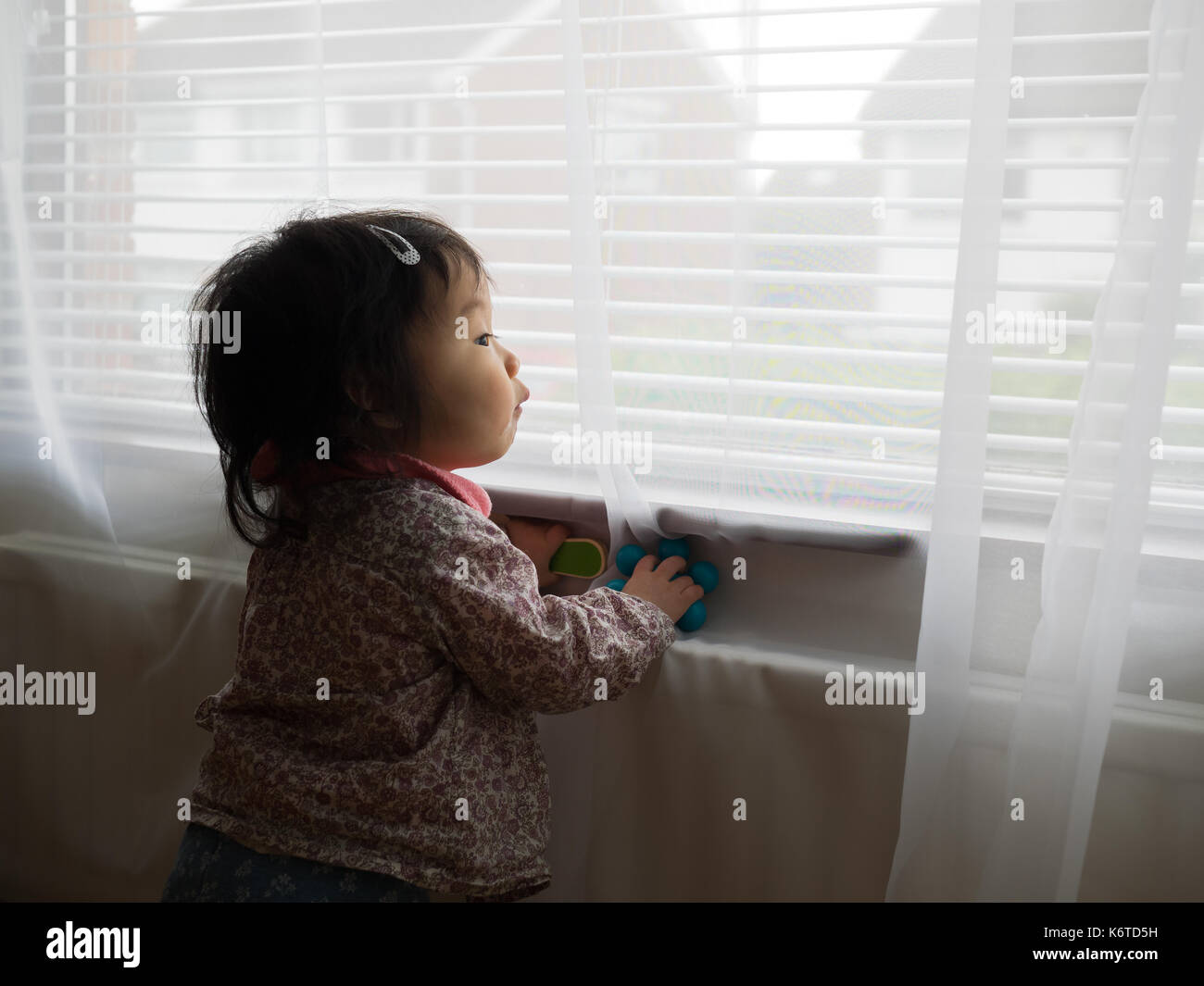 baby girl looking out windows Stock Photo - Alamy