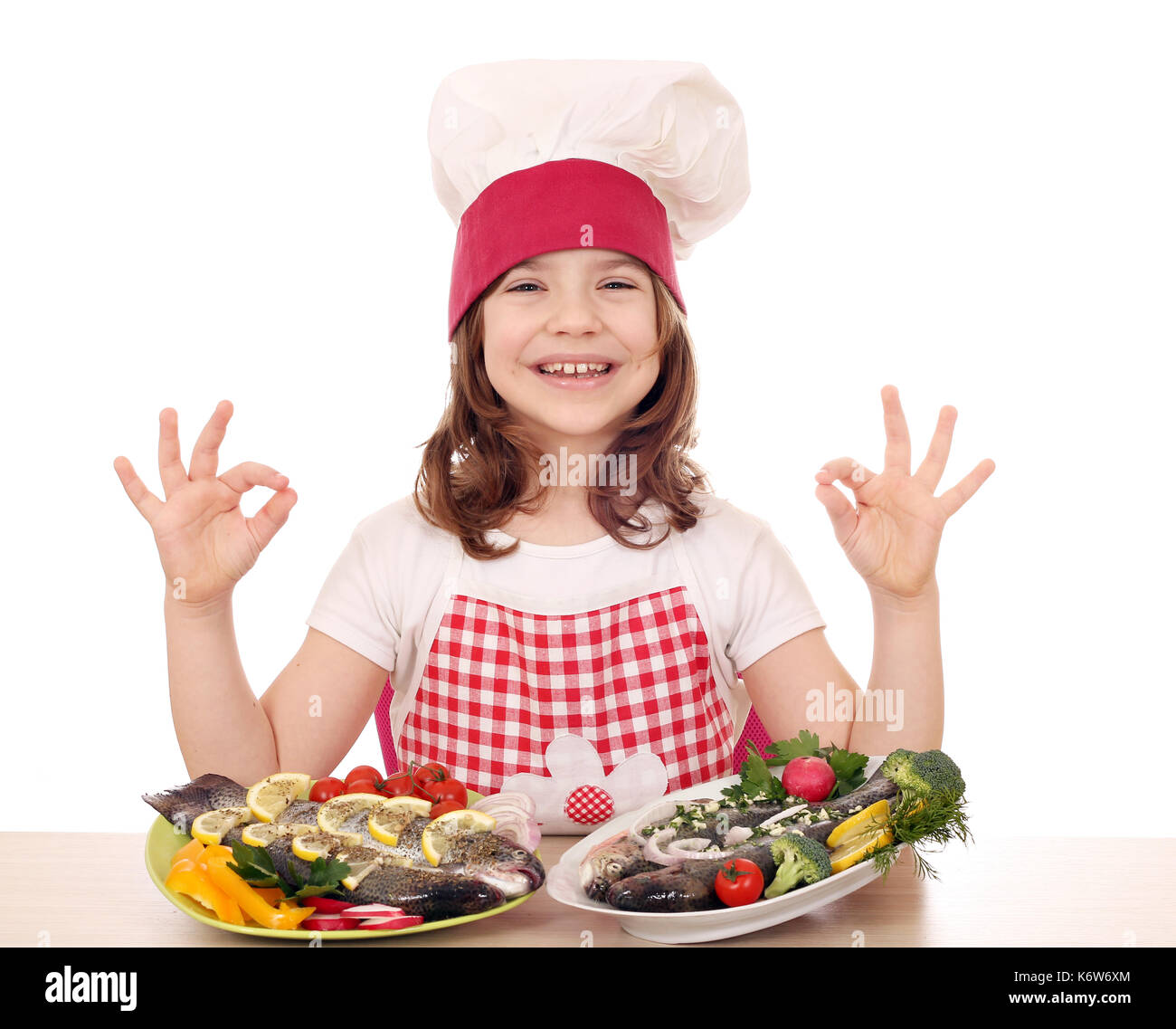happy little girl cook with fishes and ok hand sign Stock Photo - Alamy