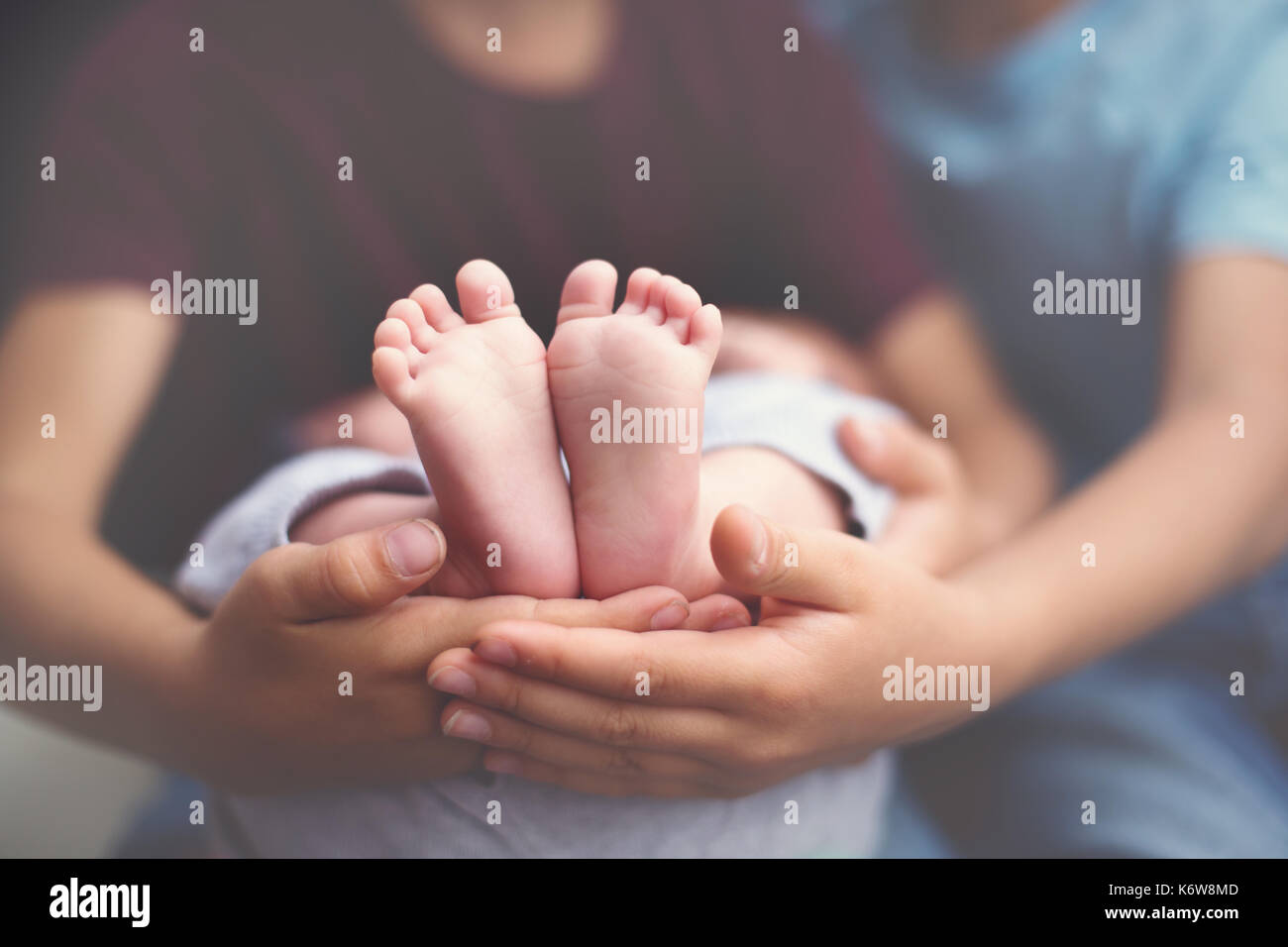Little baby feet in brothers hands, two children holding their baby ...