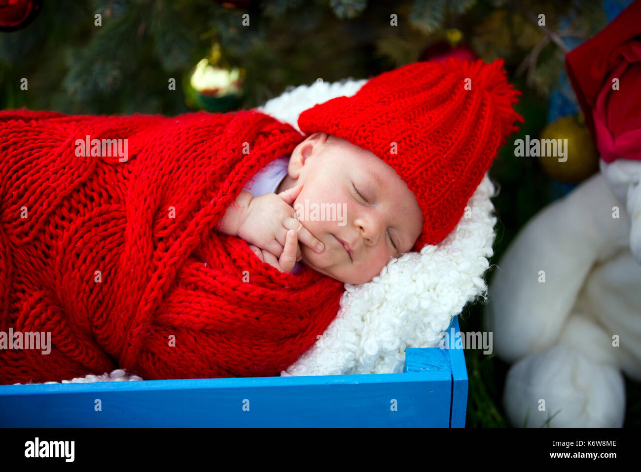 Portrait of newborn baby in Santa clothes lying under Christmas tree ...
