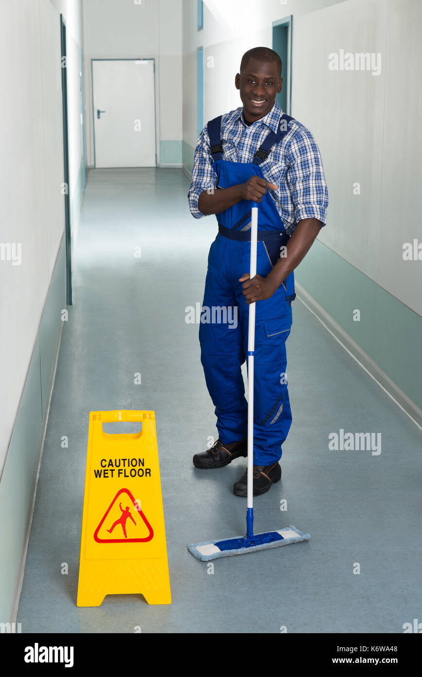 Young African Male Janitor Cleaning Floor In Corridor Stock Photo - Alamy