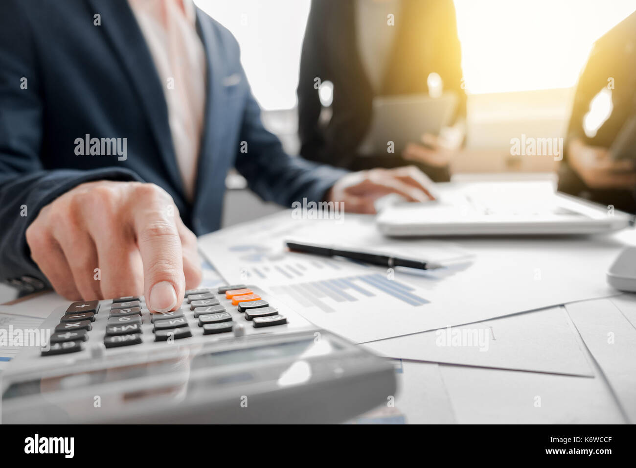 Business team using a calculator to calculate the numbers on his desk ...