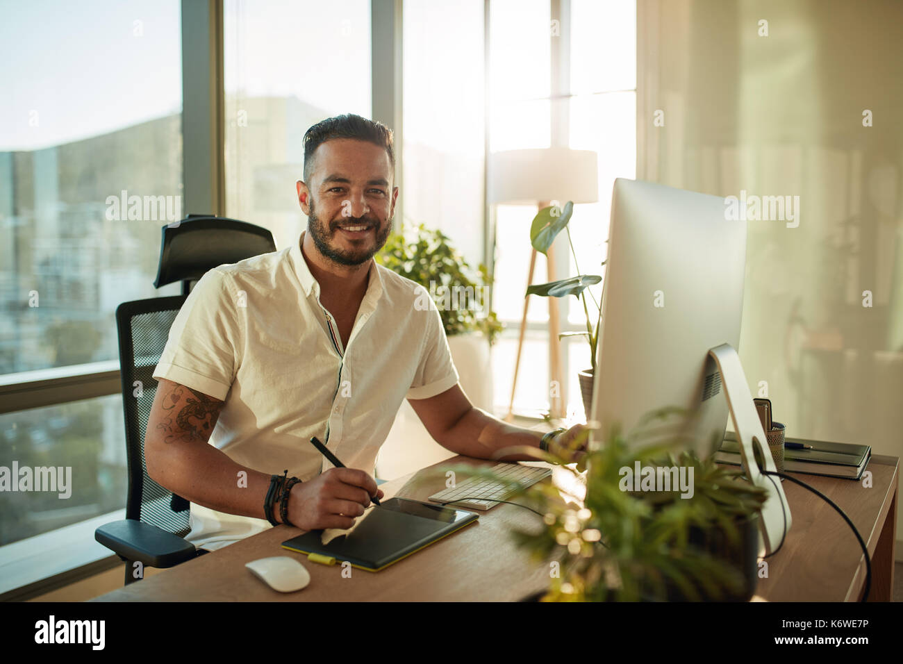 Portrait of creative young man working in office with graphic tablet ...