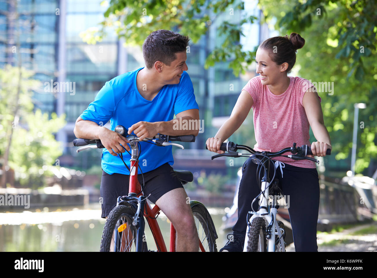 Young Couple Cycling Next To River In Urban Setting Stock Photo - Alamy