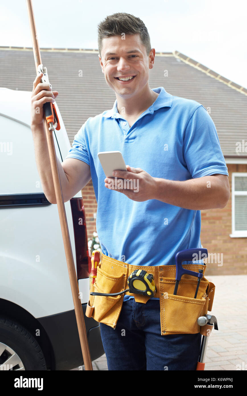 Portrait Of Plumber With Van Texting On Mobile Phone Outside House ...