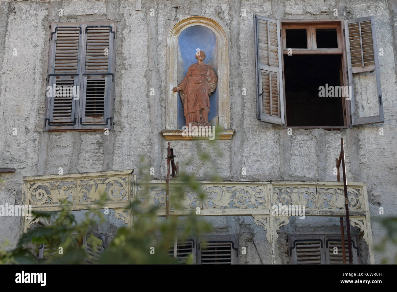 Decayed building facade with weathered statue in niche alcove arched ...