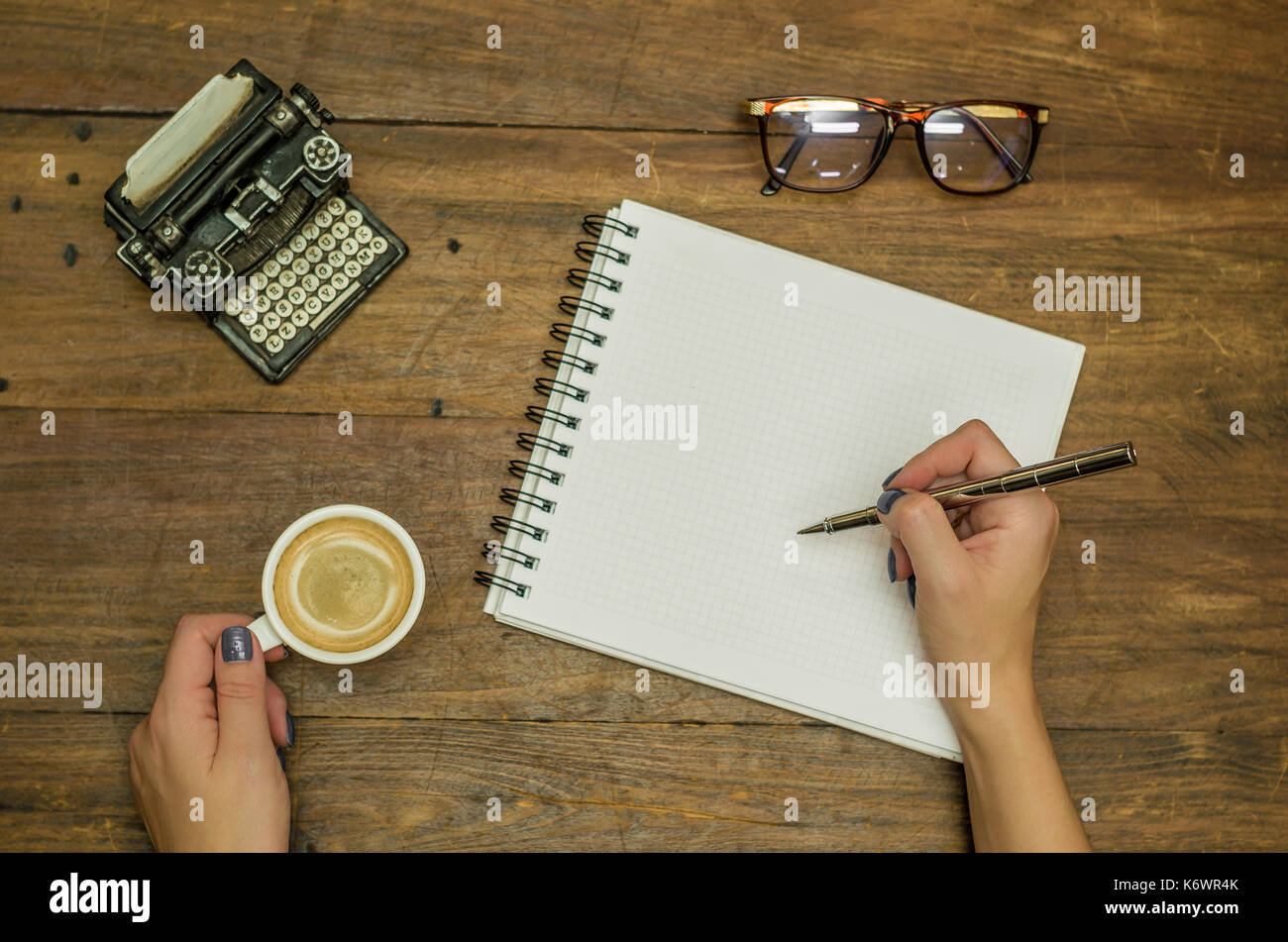 Woman hand writing in notebook, drinking coffee. Table with rustic wood ...