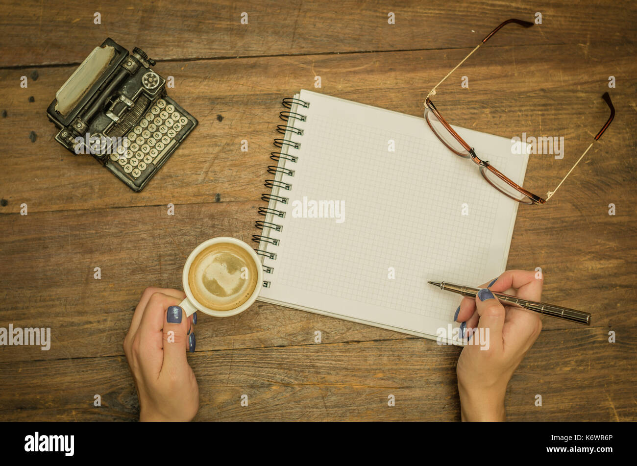 Woman hand writing in notebook, drinking coffee. Table with rustic wood ...