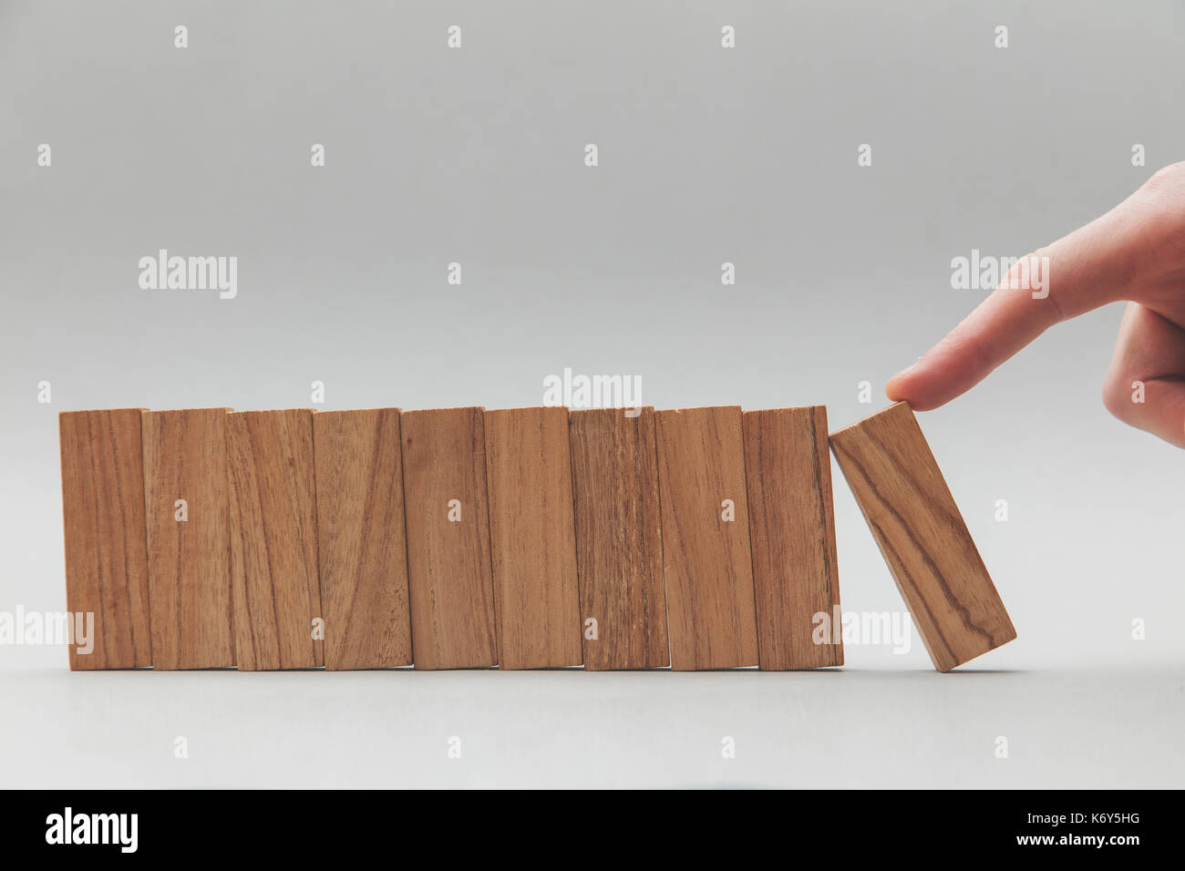 Male hand stopping wooden blocks falling over Stock Photo - Alamy