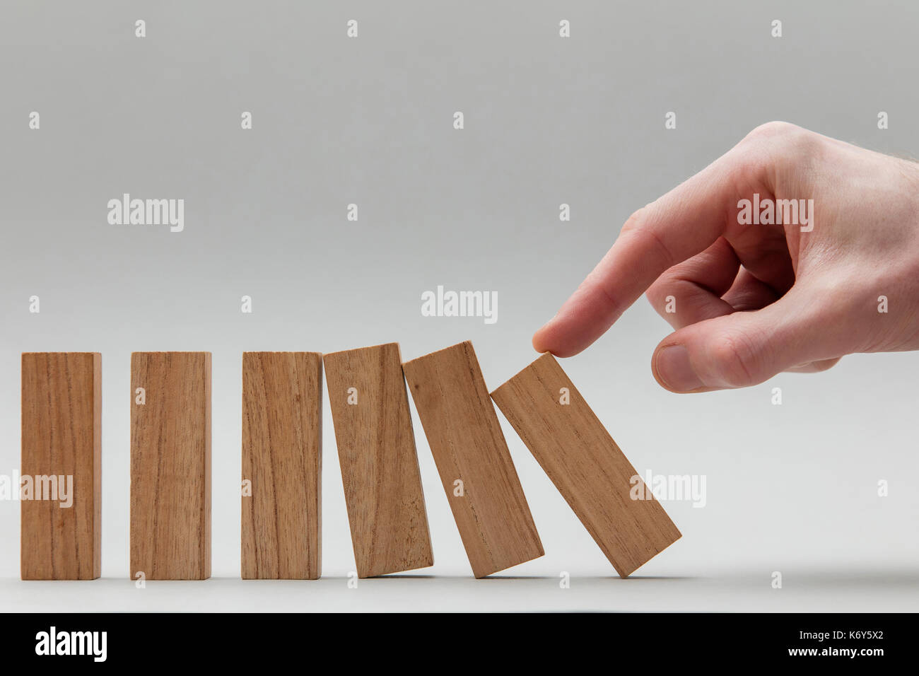 Male hand stopping wooden blocks falling over Stock Photo - Alamy