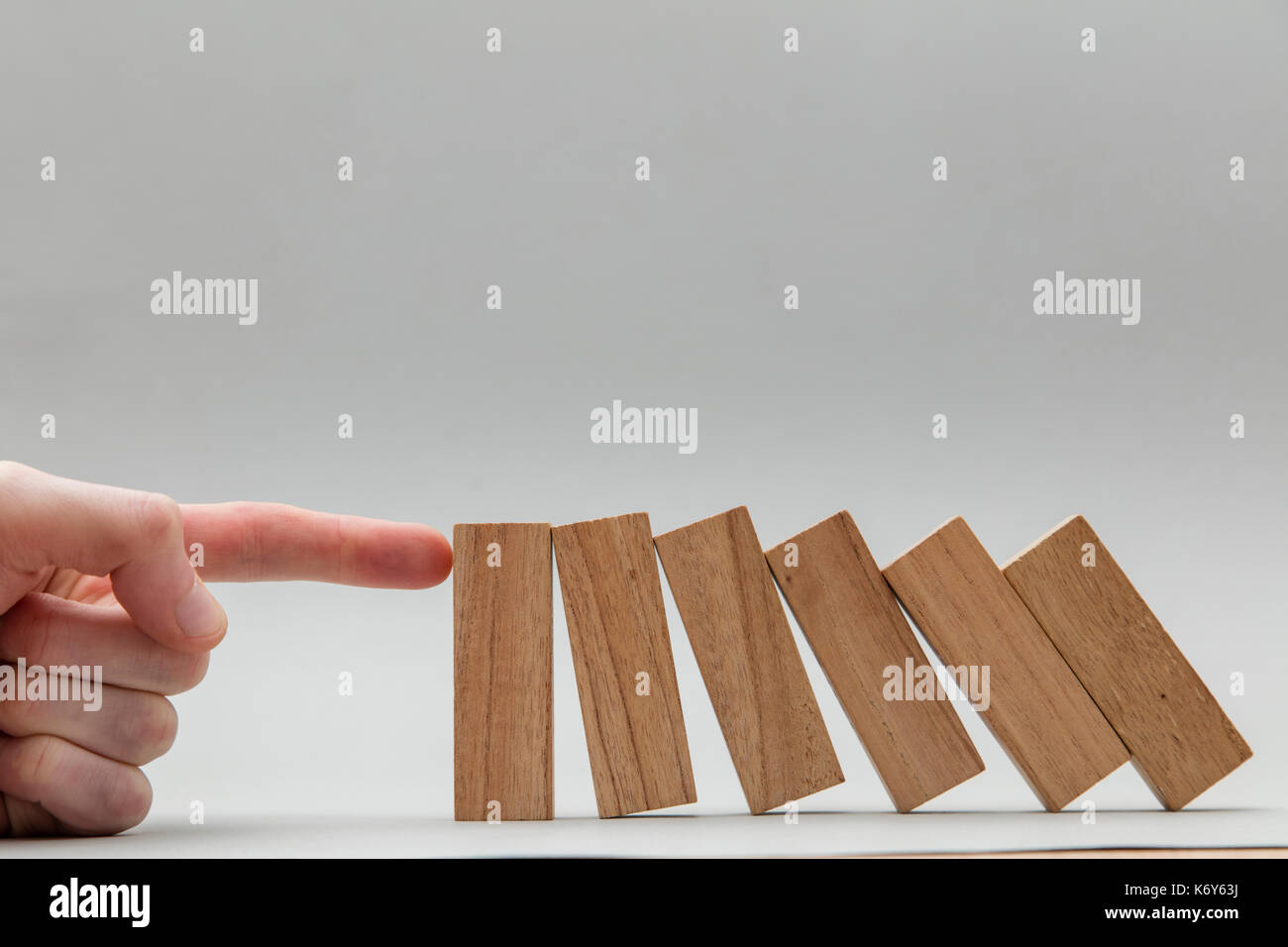 Male hand stopping wooden blocks falling over Stock Photo - Alamy