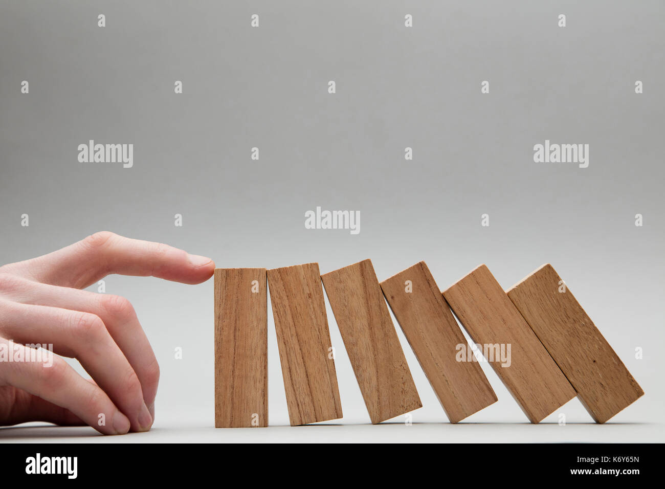 Male hand stopping wooden blocks falling over Stock Photo - Alamy