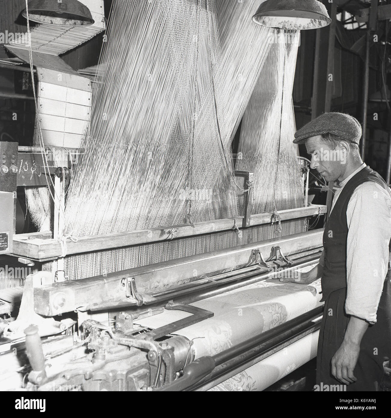 1950s, Northern ireland, a male textile worker in a waistcoat and cap ...