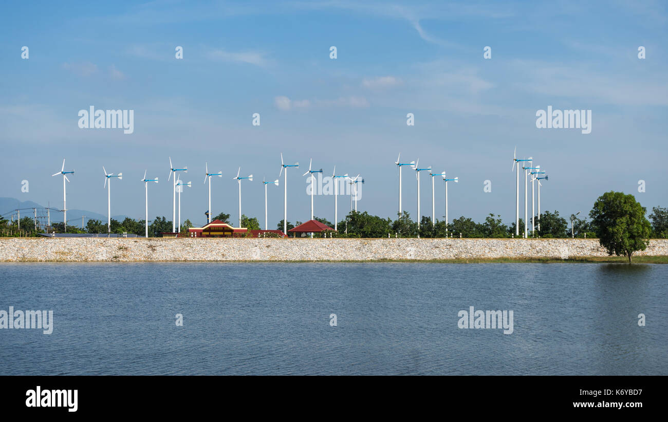 Group of wind turbines behind lake with blue sky Stock Photo - Alamy