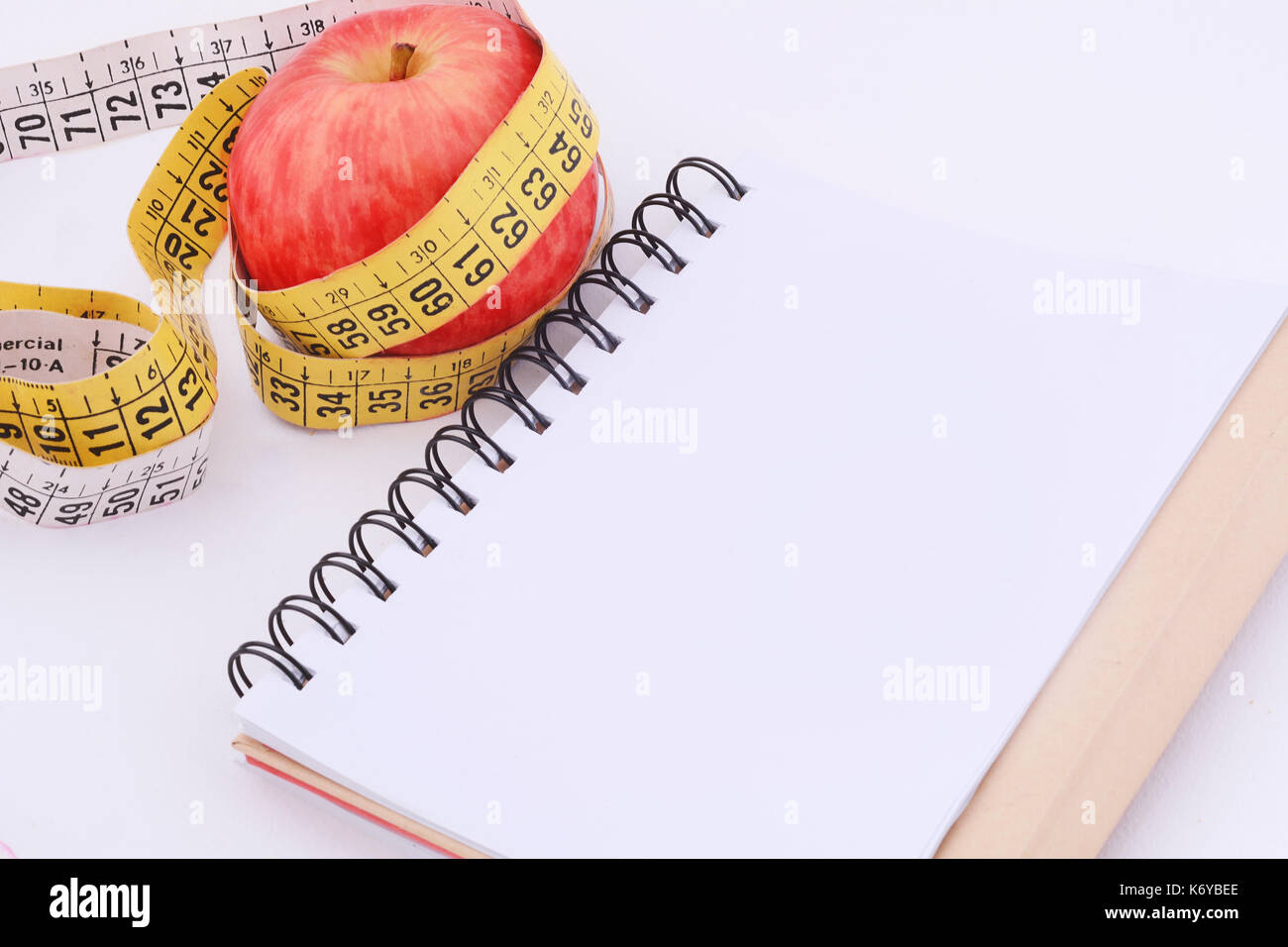 An apple and measuring tape on notepad. Healthy food concept. Isolated ...