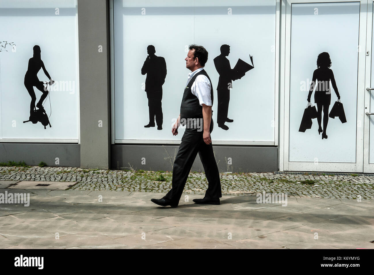 A waiter walks along Schutzenstrasse, Berlin Stock Photo - Alamy