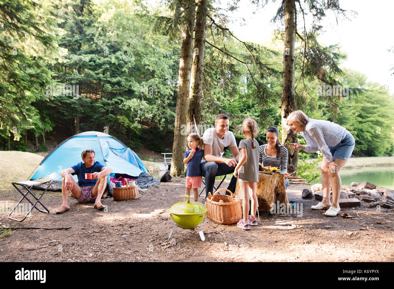 Beautiful family camping in forest, eating together Stock Photo - Alamy