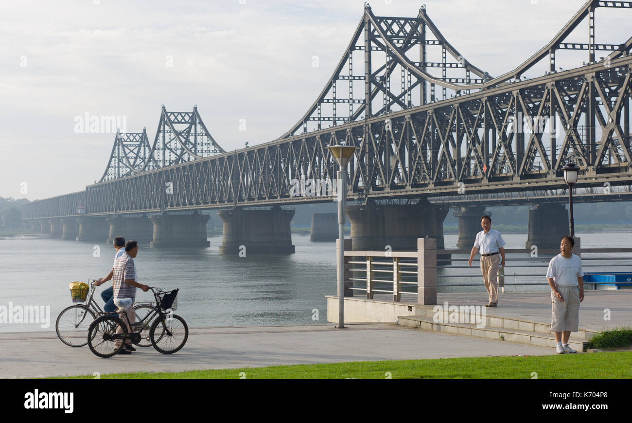Walkers and cyclists on Chinese embankment alongside Yalu River with ...