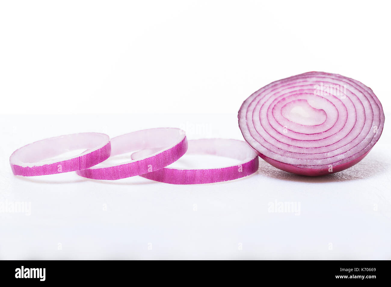 Three sliced red onion rings along with half of onion on white ...