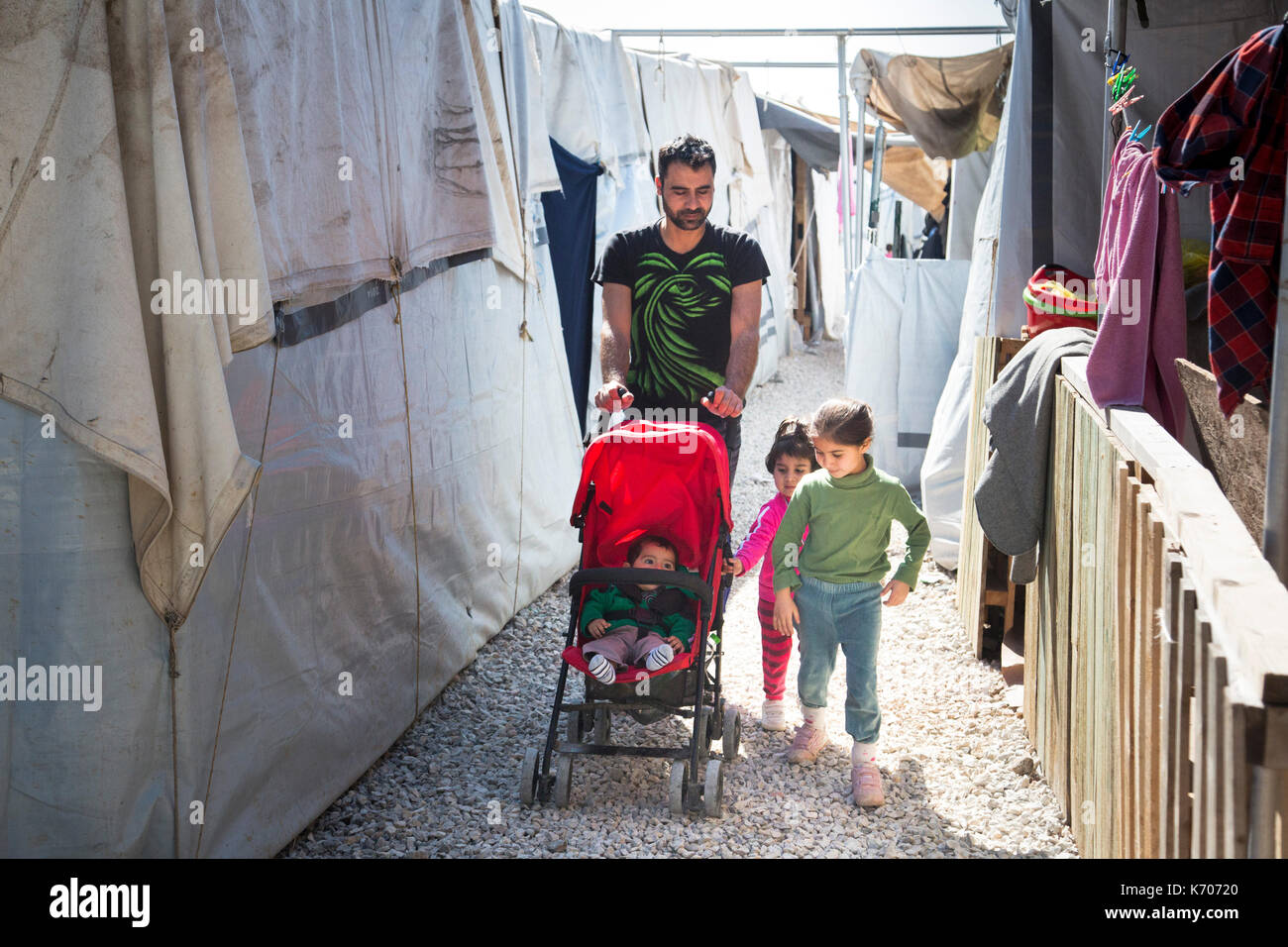A father with two young girls at his side, pushes a stroller carrying ...