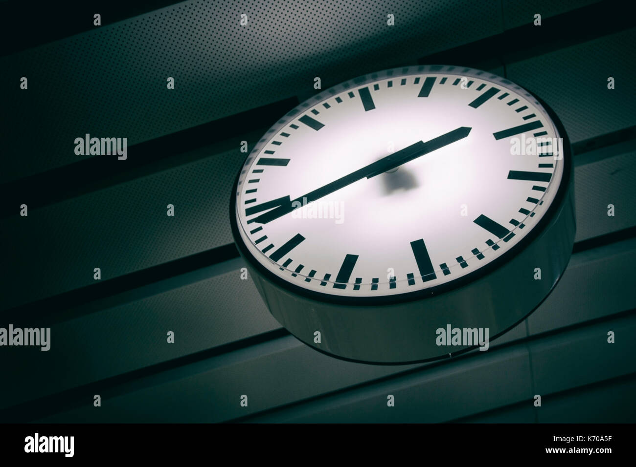 A white clock is hanging down from the ceiling Stock Photo - Alamy