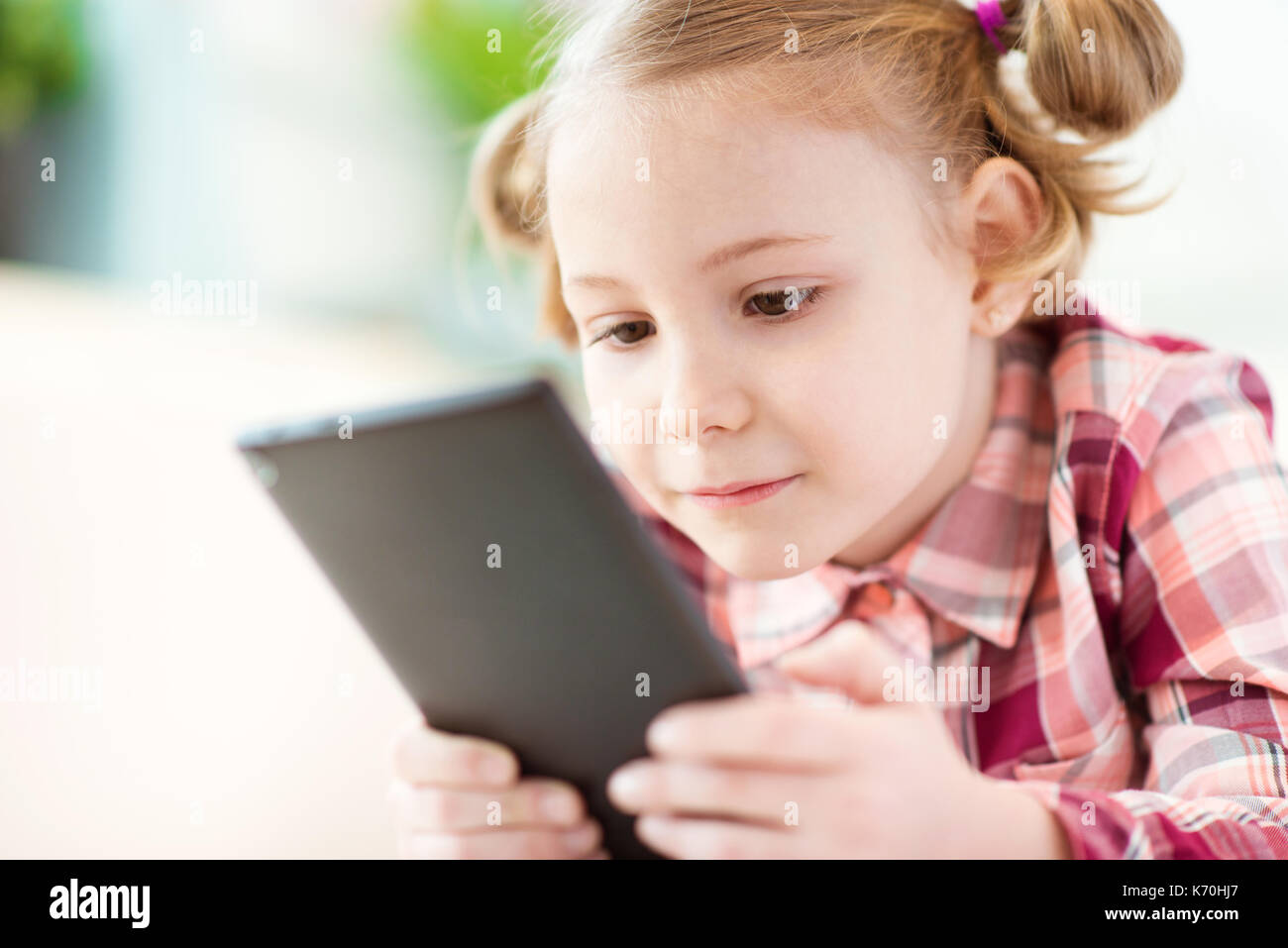 Pretty little child girl using a digital tablet, looking and smiling ...