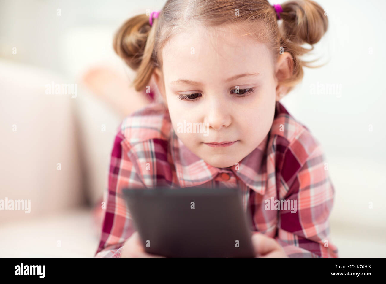 Pretty little child girl using a digital tablet, looking and smiling ...