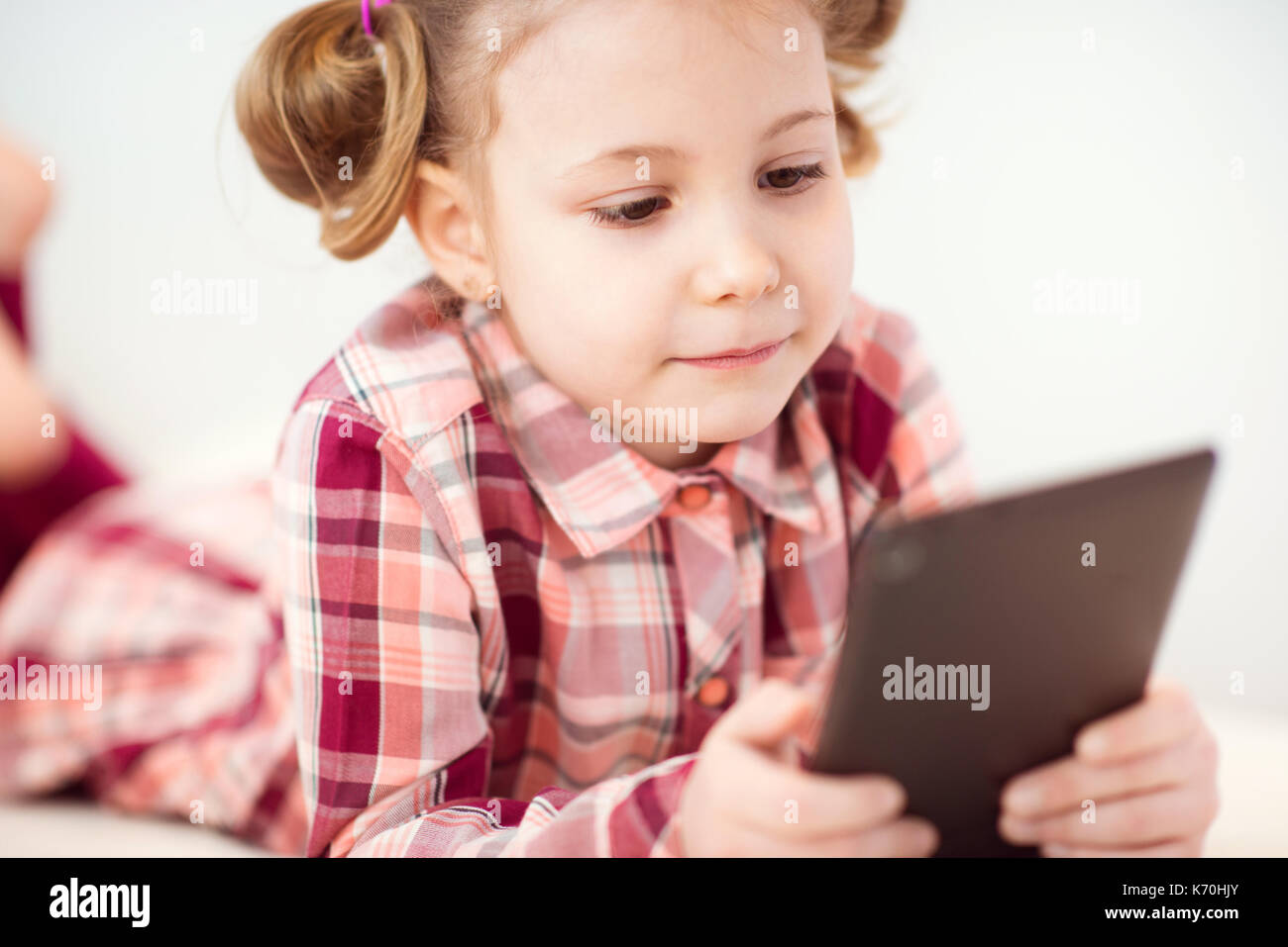 Pretty little child girl using a digital tablet, looking and smiling ...