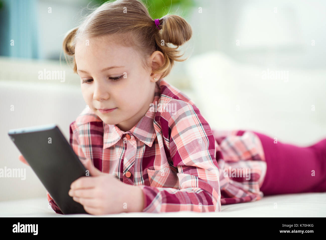 Pretty little child girl using a digital tablet, looking and smiling ...