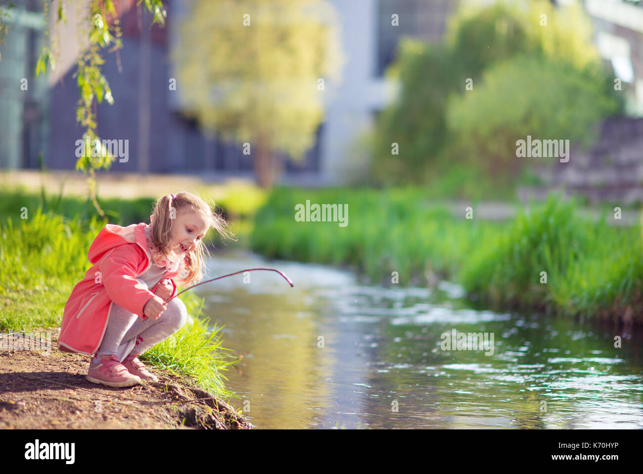 Happy adorable little blonde girl playing near pond in sunny day Stock ...