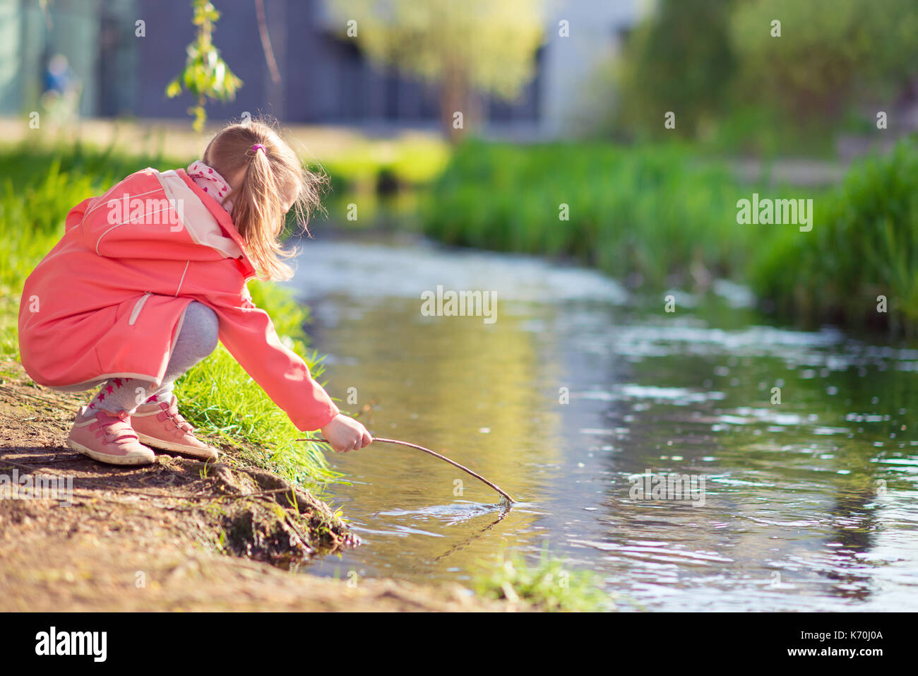 Happy adorable little blonde girl playing near pond in sunny day Stock ...