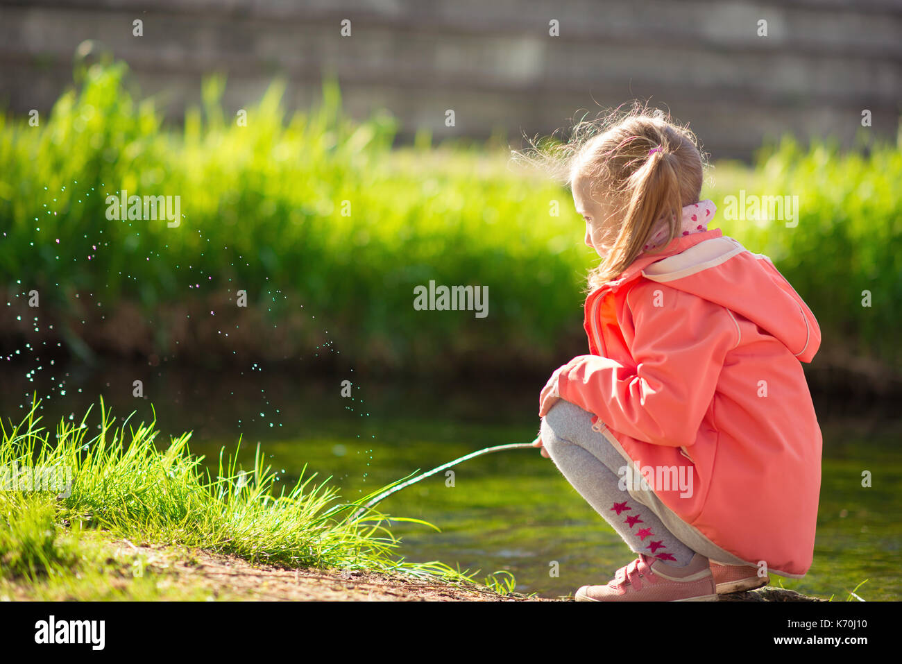 Happy adorable little blonde girl playing near pond in sunny day Stock ...