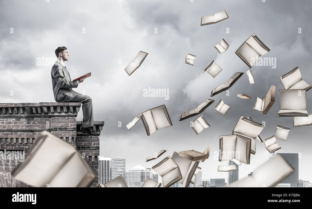 Man on roof reading book and many of them flying in air Stock Photo - Alamy