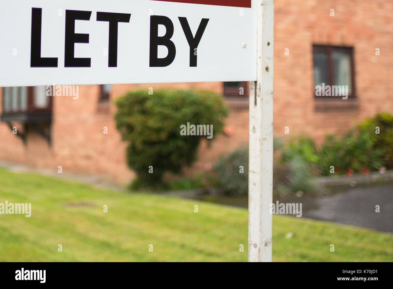 Let by sign with red brick house in the background Stock Photo - Alamy