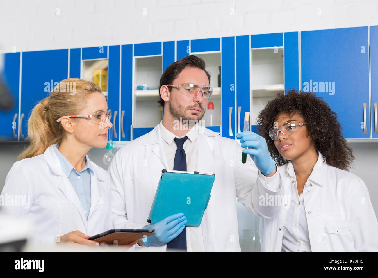 Group of Laboratory Scientists Examining Green Liquid In Test Tube ...