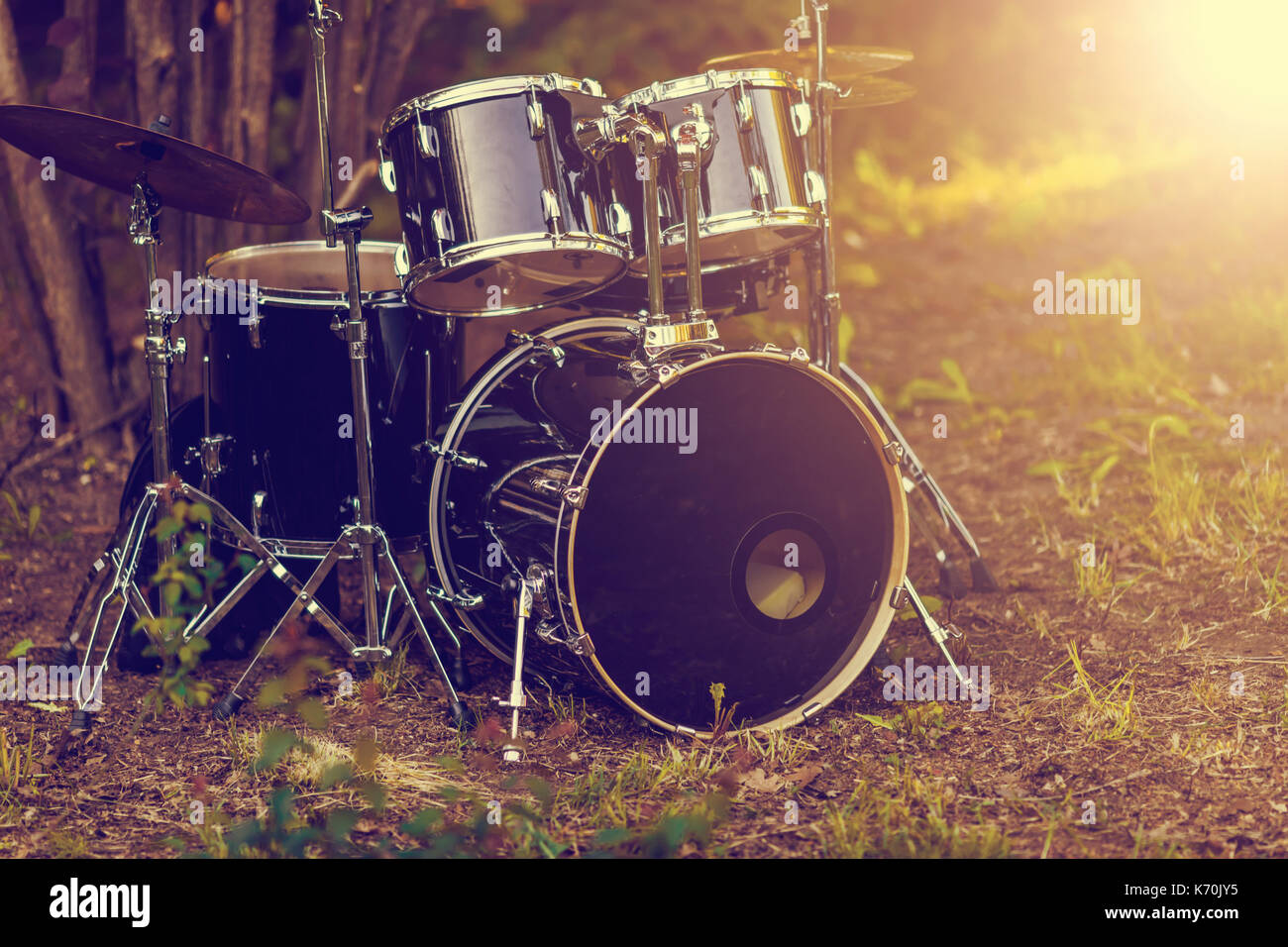 Set of black battery drum set under the tree on the grass. Vintage tone ...