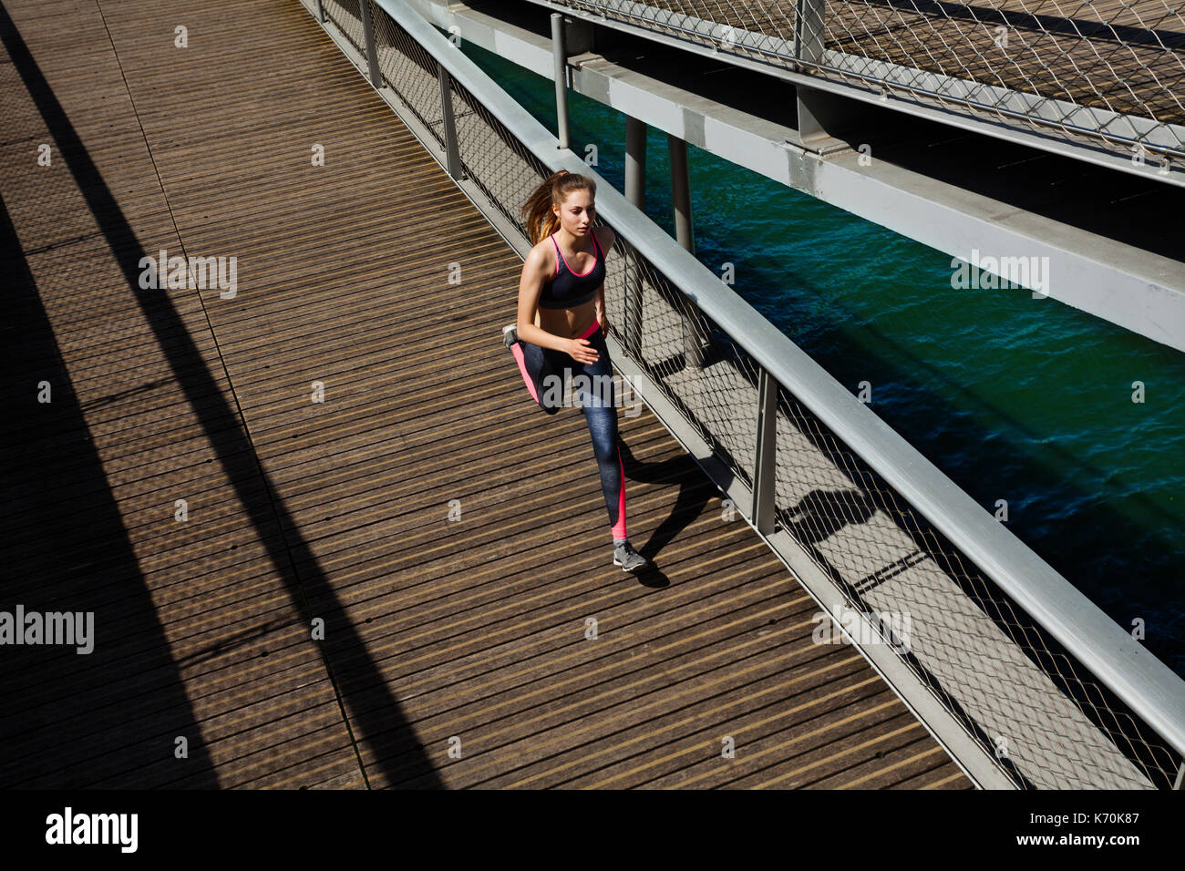 Top view portrait of sportswoman running and sprinting across a bridge ...