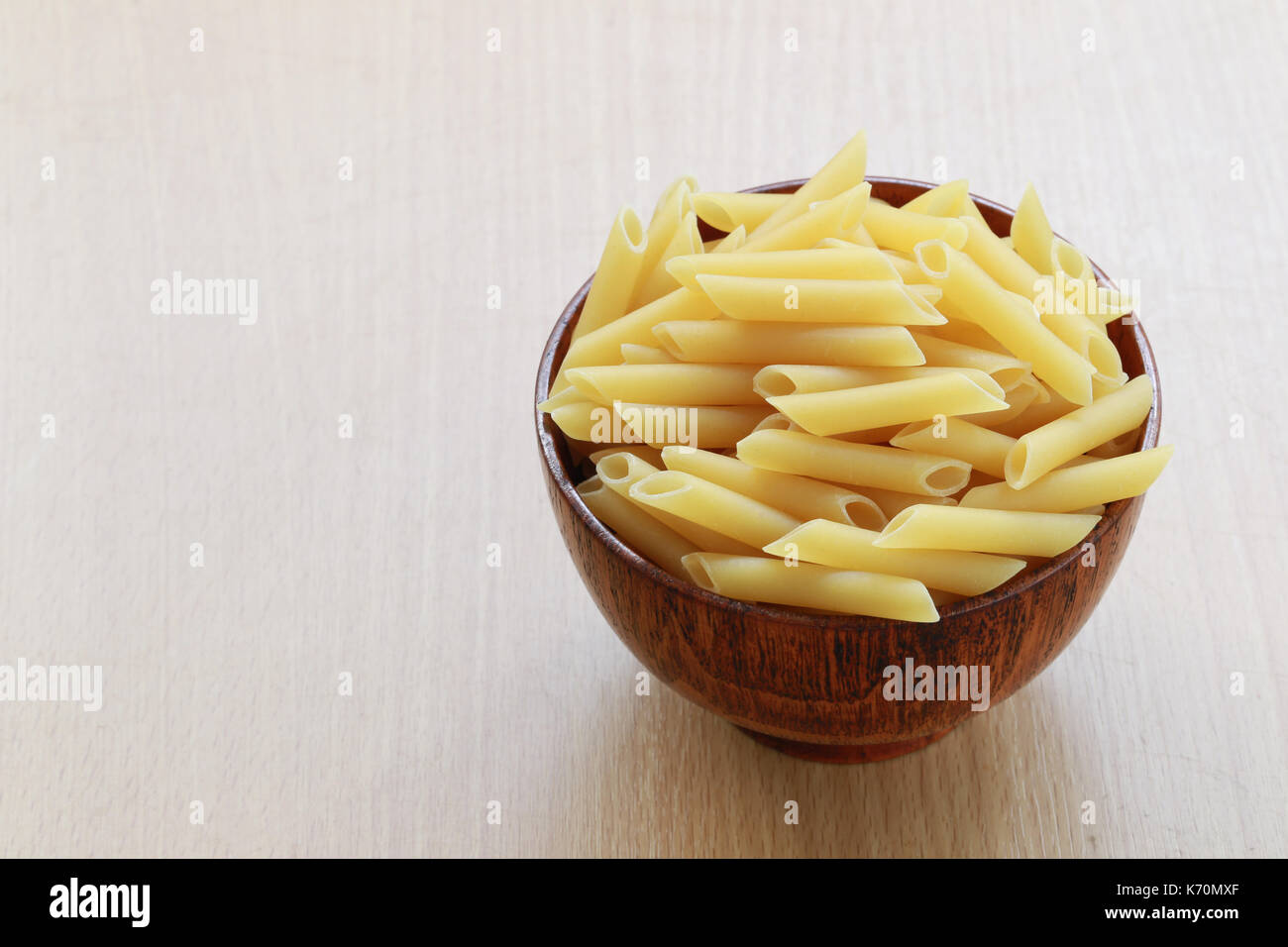 Raw Macaroni in the wooden bowl on wood background for design in your ...